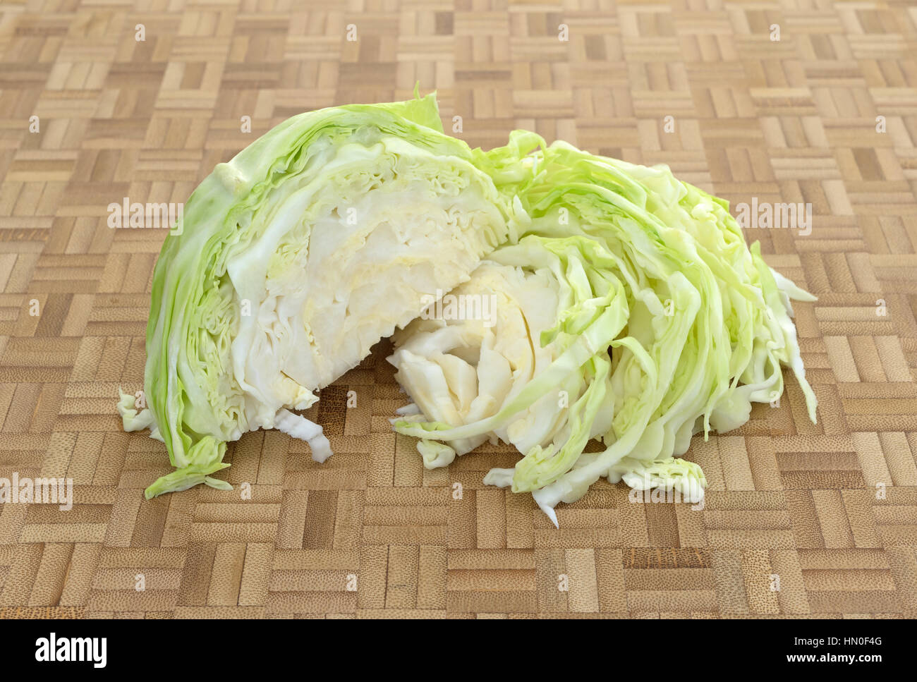 A portion of organic cabbage that has been sliced on a wood cutting ...