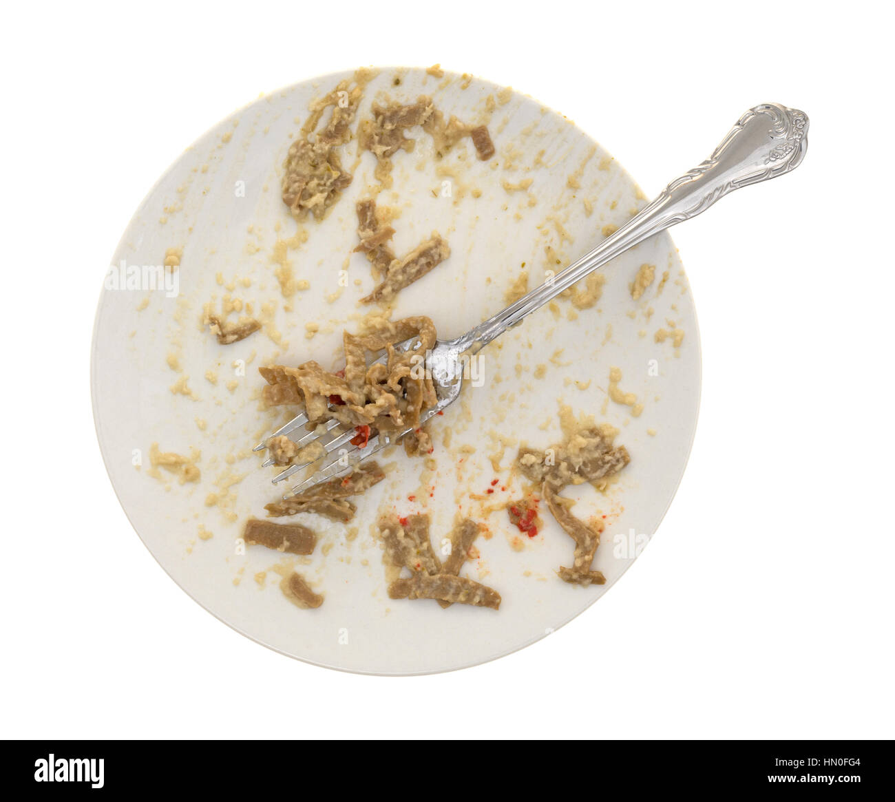 A dirty dish with leftover edamame fettuccine plus a fork isolated on a ...