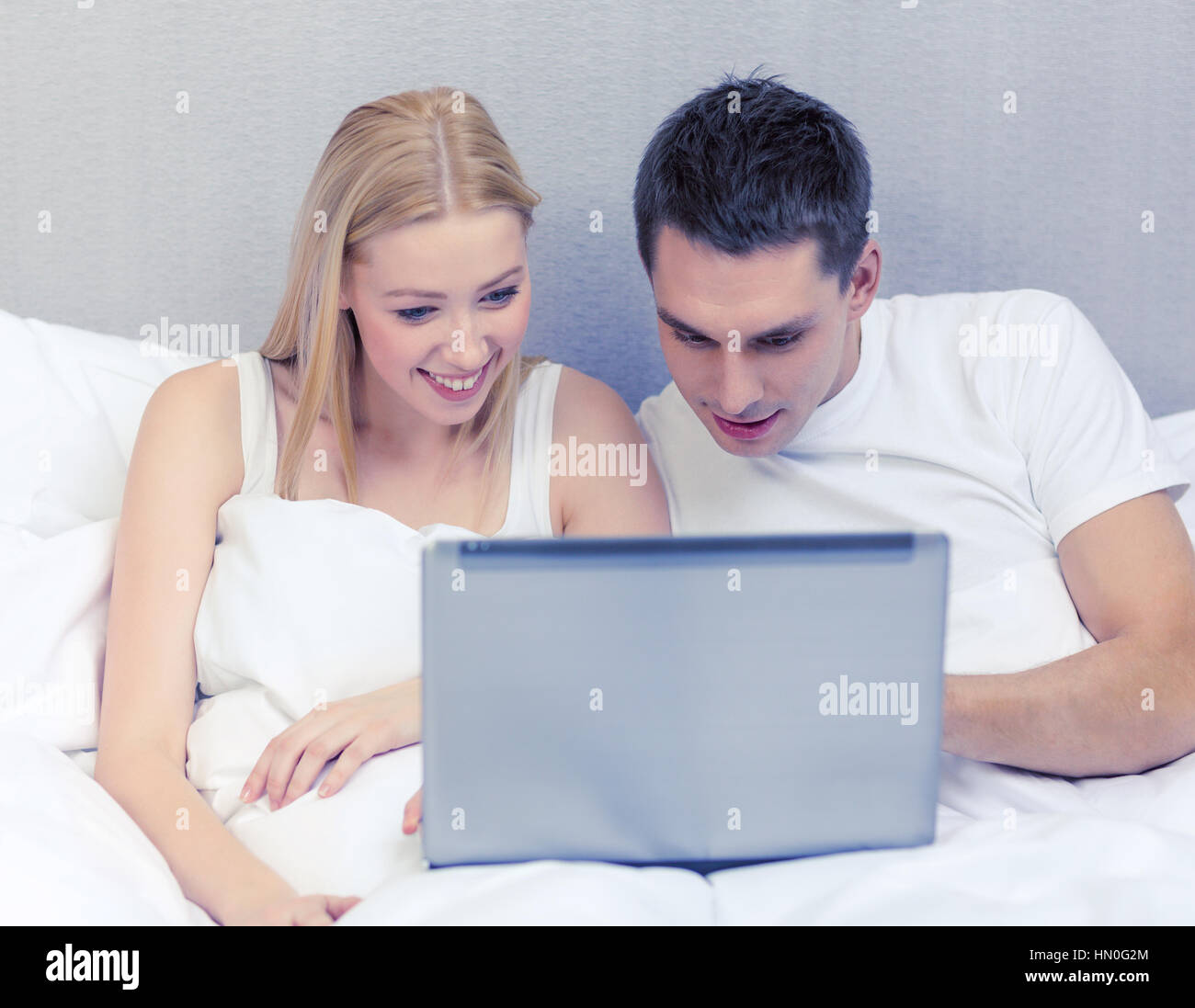 smiling couple in bed with laptop computer Stock Photo - Alamy