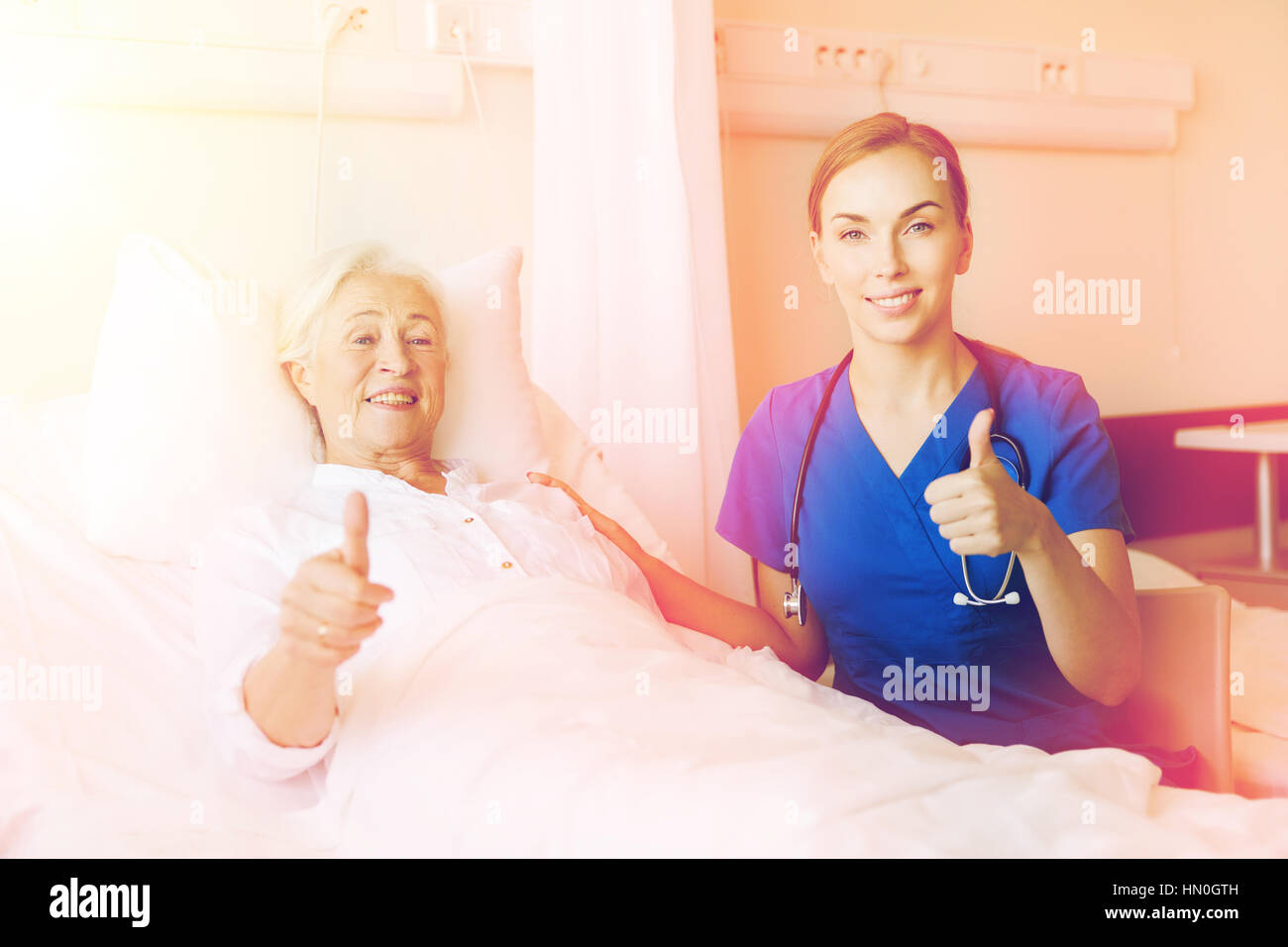 nurse and senior woman showing thumbs up at clinic Stock Photo - Alamy