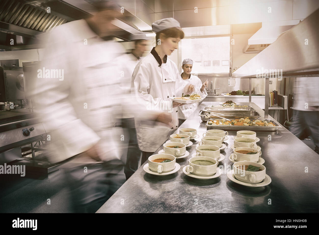 Four chefs working in a modern kitchen preparing soups and dishes Stock ...