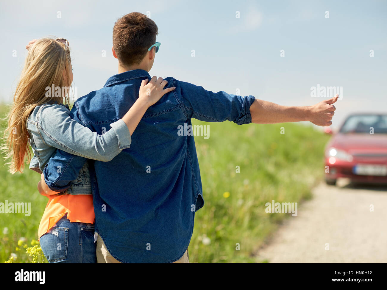 couple hitchhiking and stopping car on countryside Stock Photo - Alamy