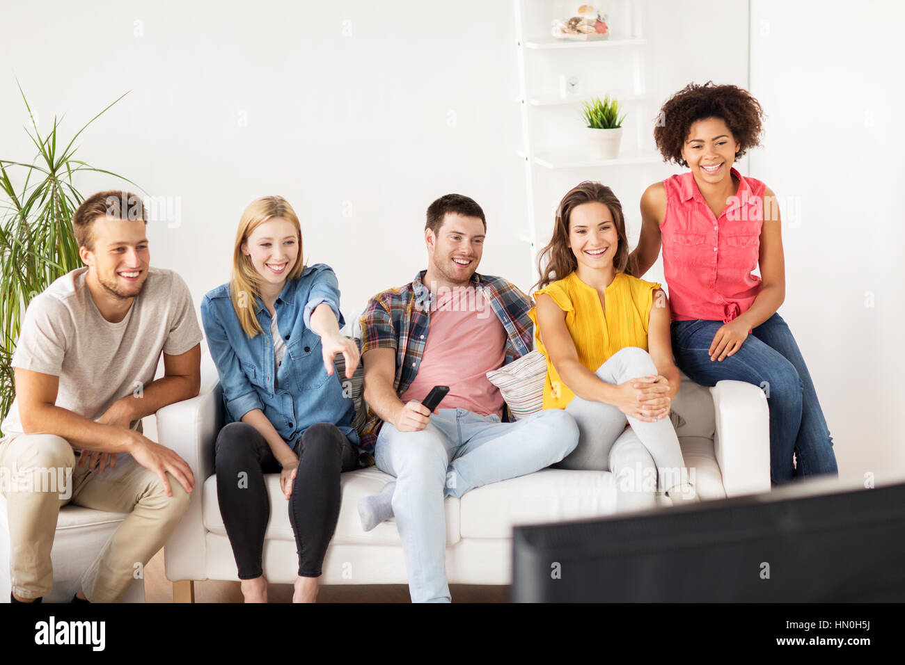 happy friends with remote watching tv at home Stock Photo - Alamy