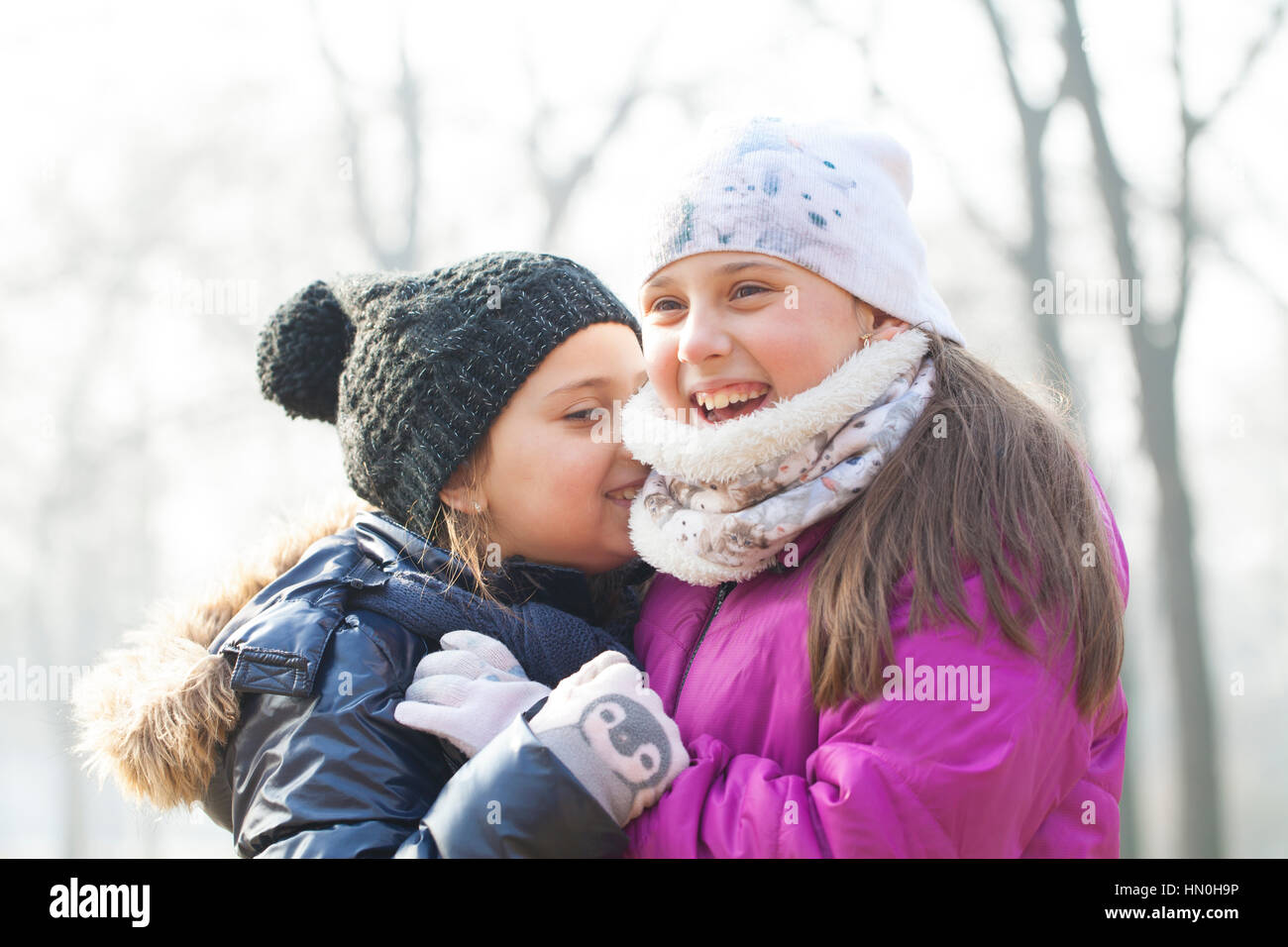 Two little girls with caps and scarves play Stock Photo - Alamy