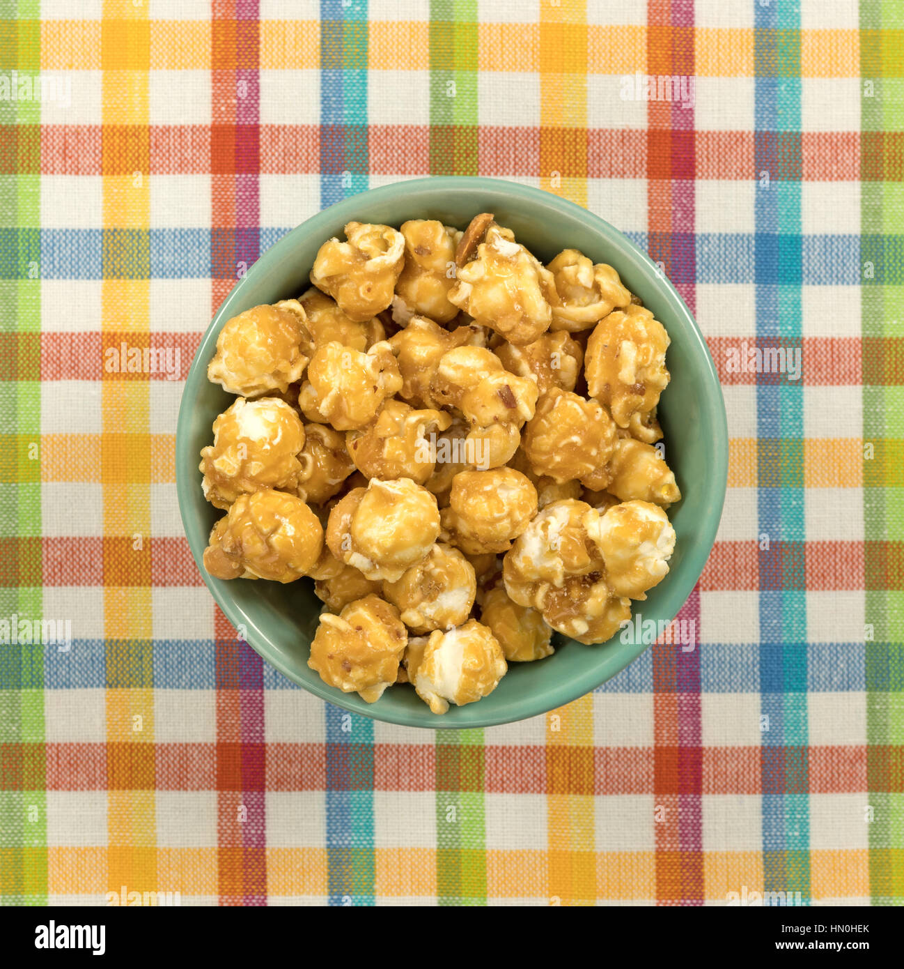 Top view of a green bowl filled with toffee caramel popcorn with nuts ...