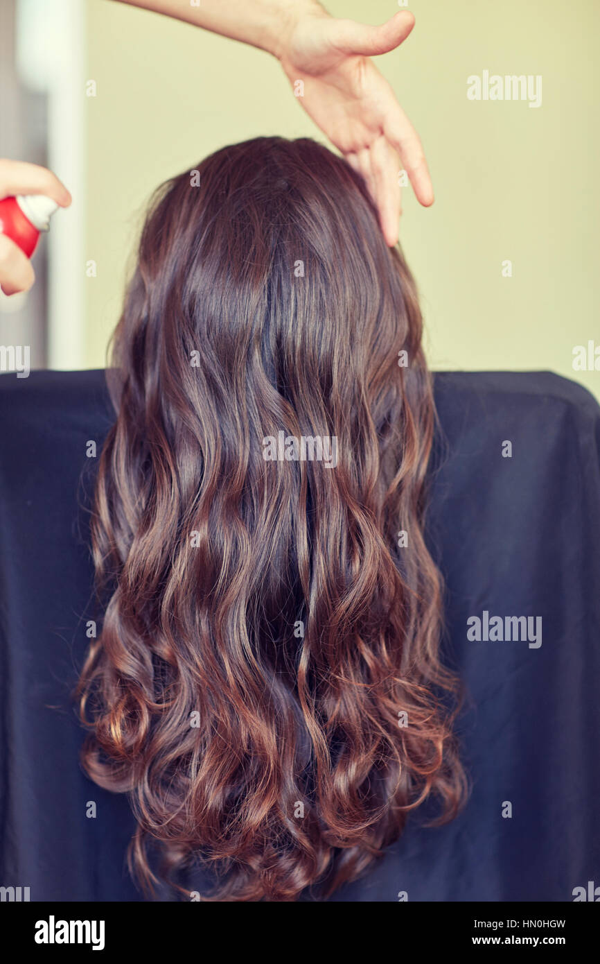 stylist with hair spray making hairdo at salon Stock Photo - Alamy
