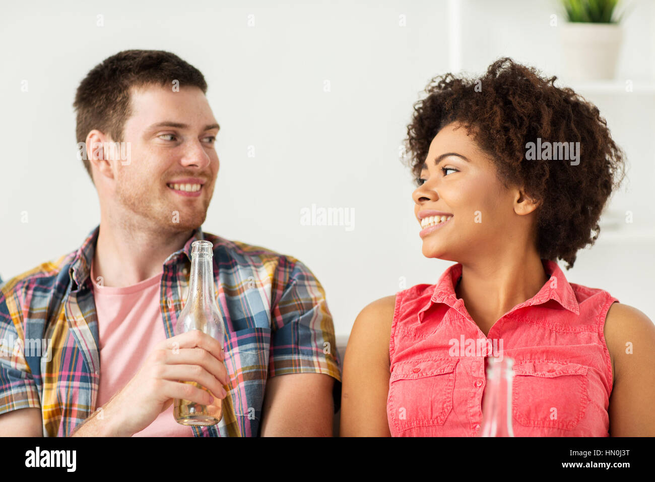 happy friends or couple with beer talking at home Stock Photo - Alamy