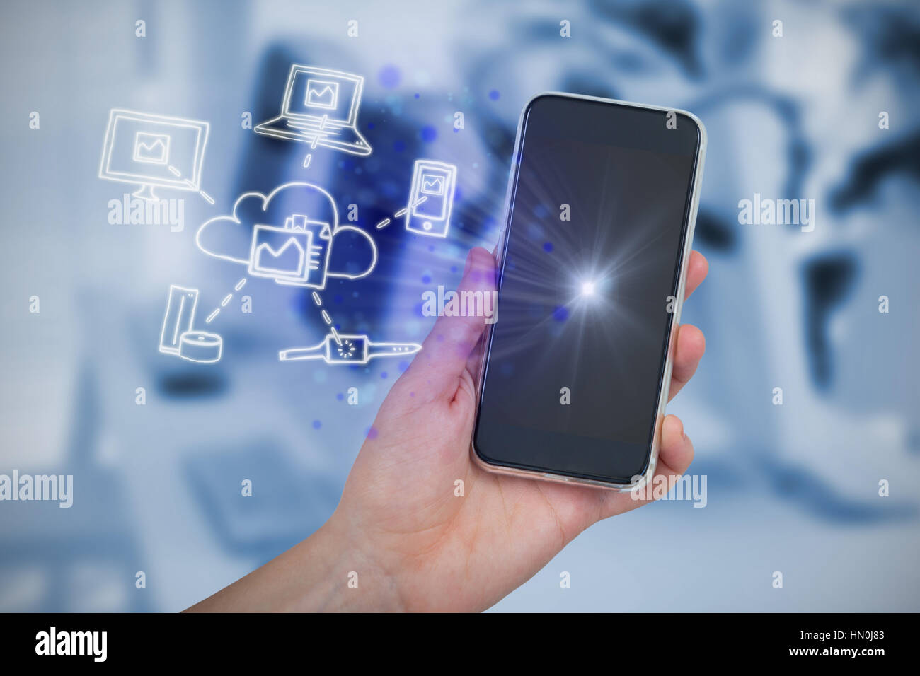 Hand holding mobile phone against white background against computers ...