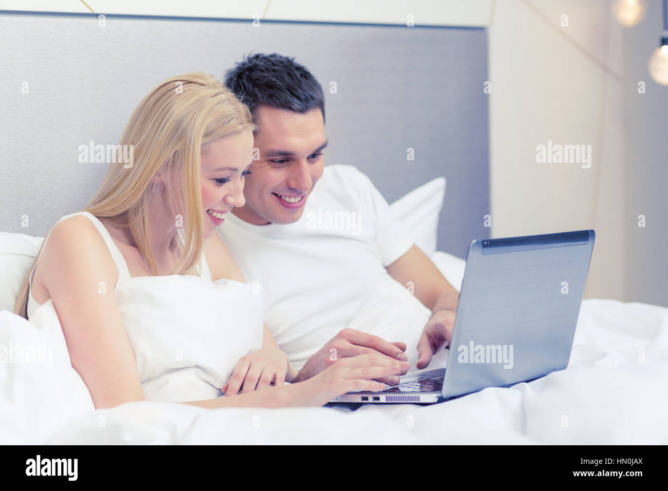 smiling couple in bed with laptop computer Stock Photo - Alamy