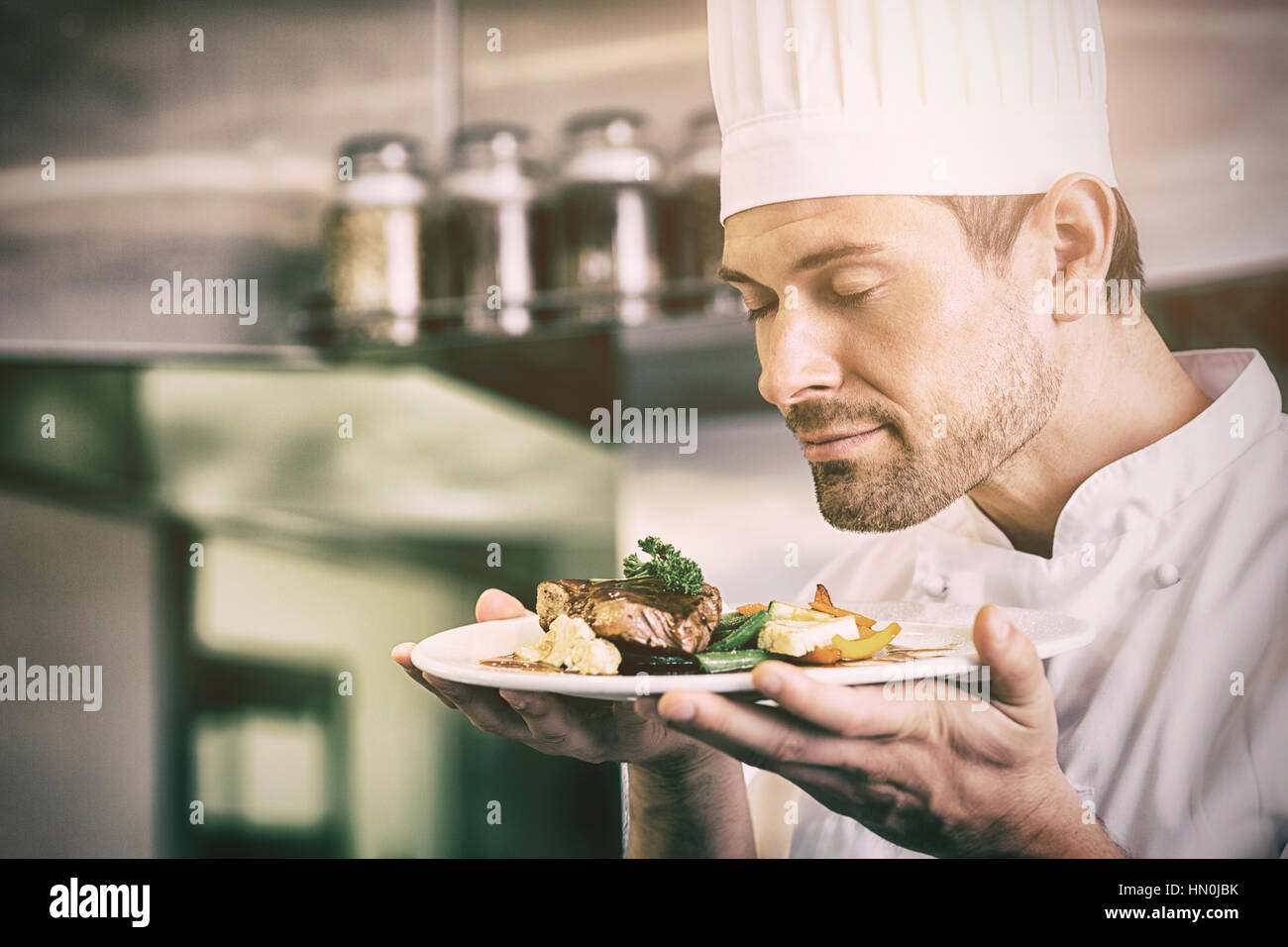 Closeup of a male chef with eyes closed smelling gourmet food in the ...