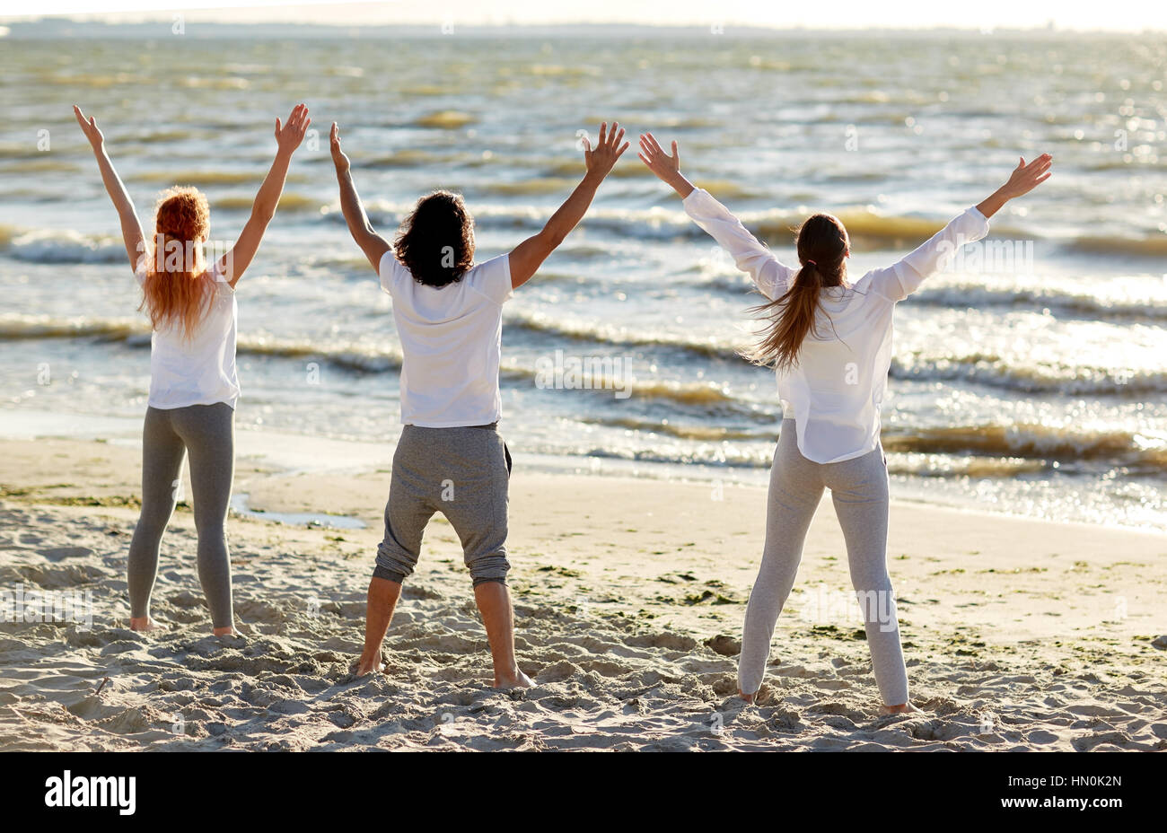 group of people making yoga or meditating on beach Stock Photo - Alamy