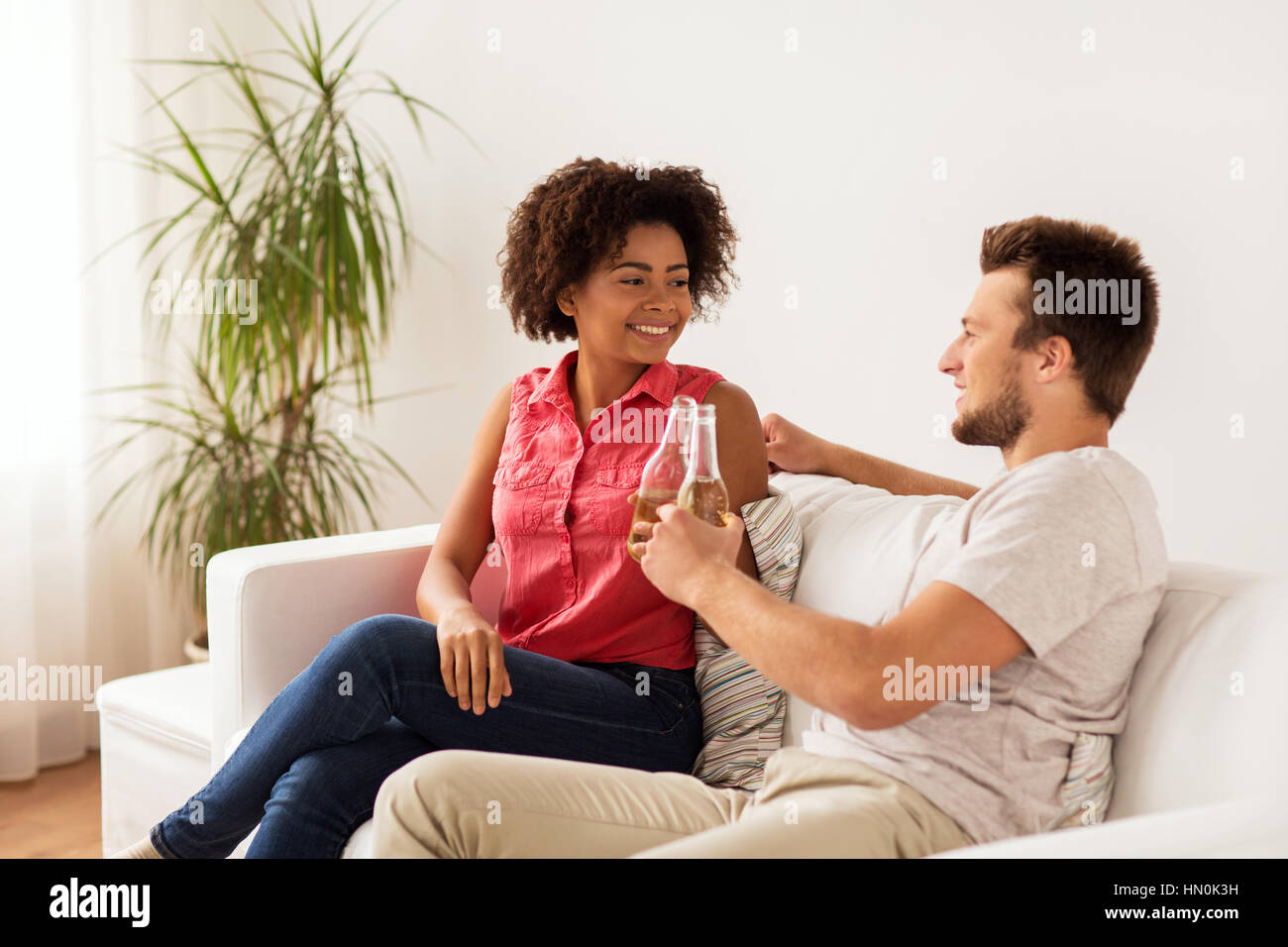 happy friends or couple with beer talking at home Stock Photo - Alamy