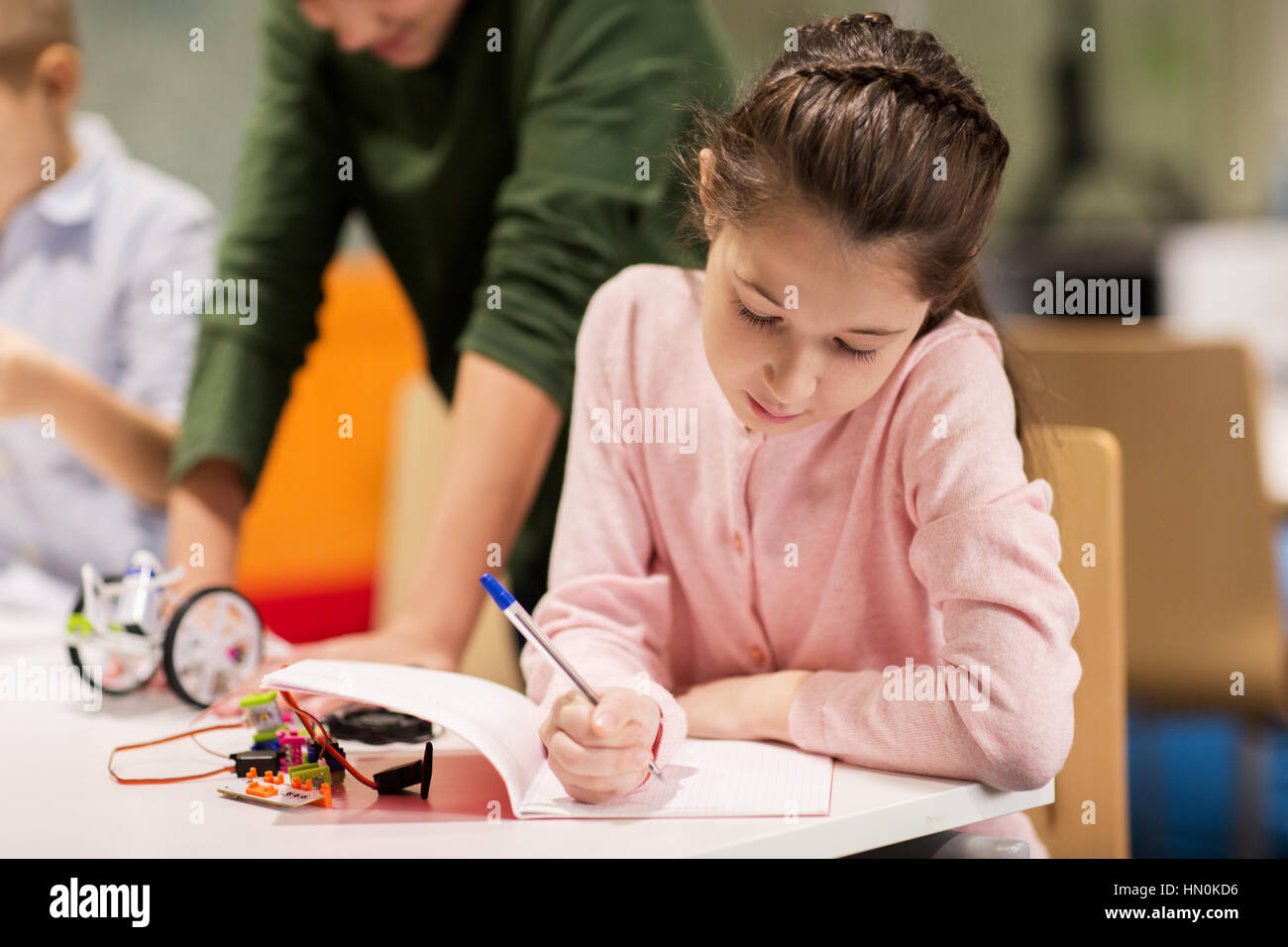 happy girl writing to notebook at robotics school Stock Photo - Alamy