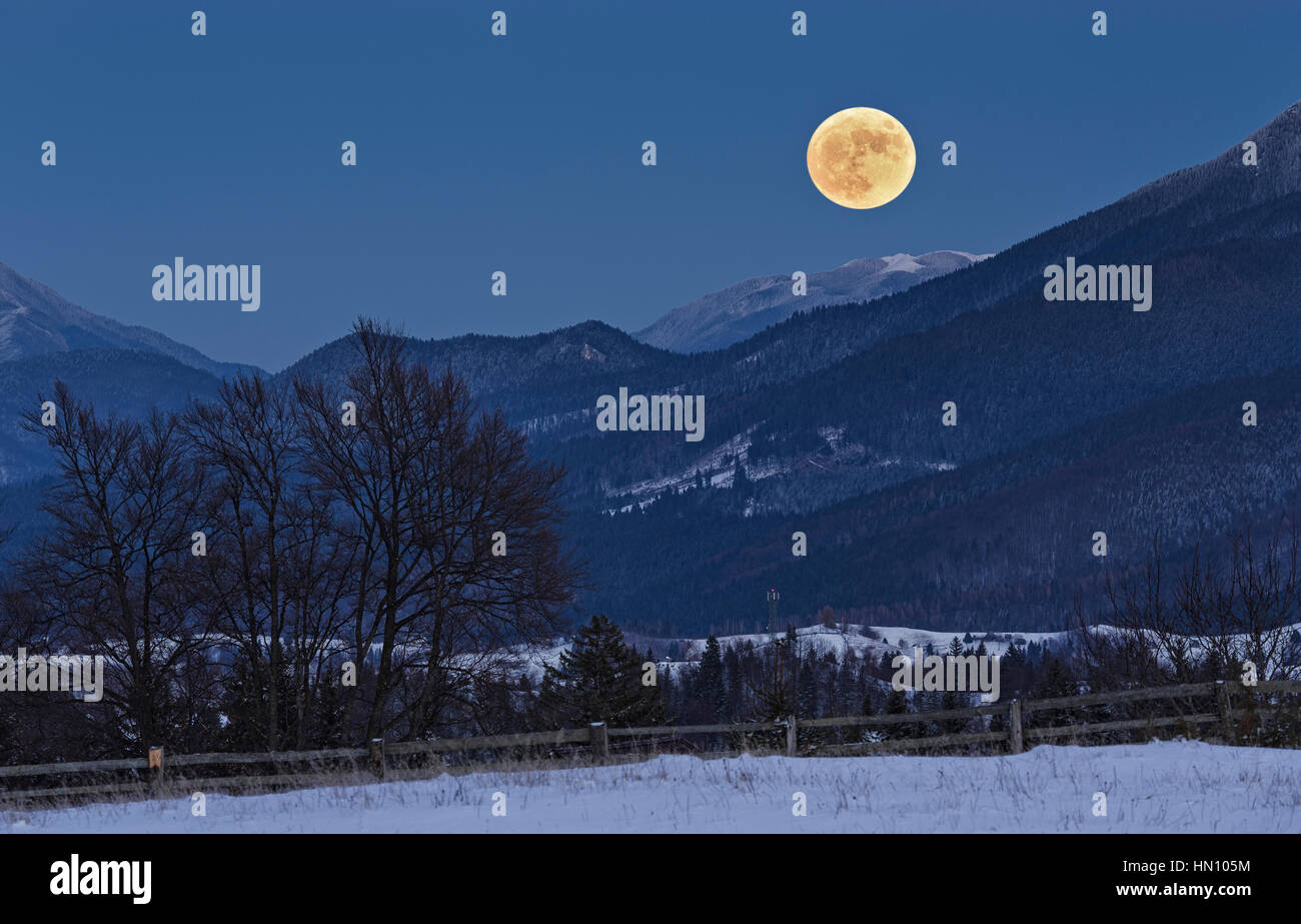 Enchanting nocturnal rural scene with full moon rising over the Piatra ...