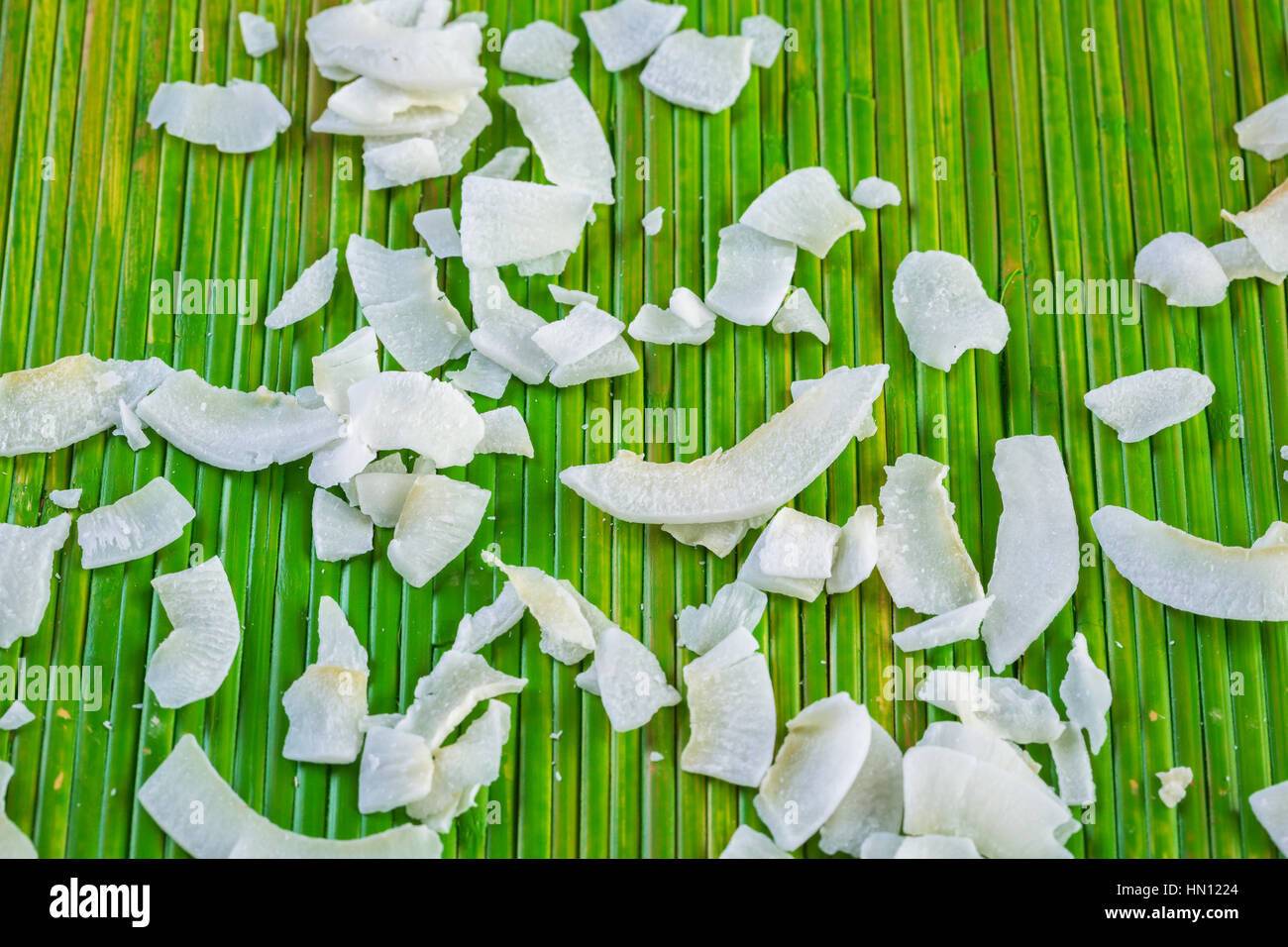 Dehydrated coconut flakes on a green background Stock Photo - Alamy
