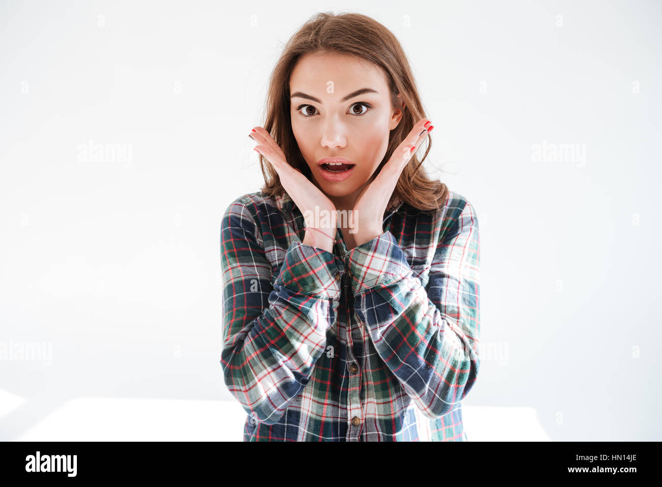 Surprised wondered young woman in plaid shirt with opened mouth over ...