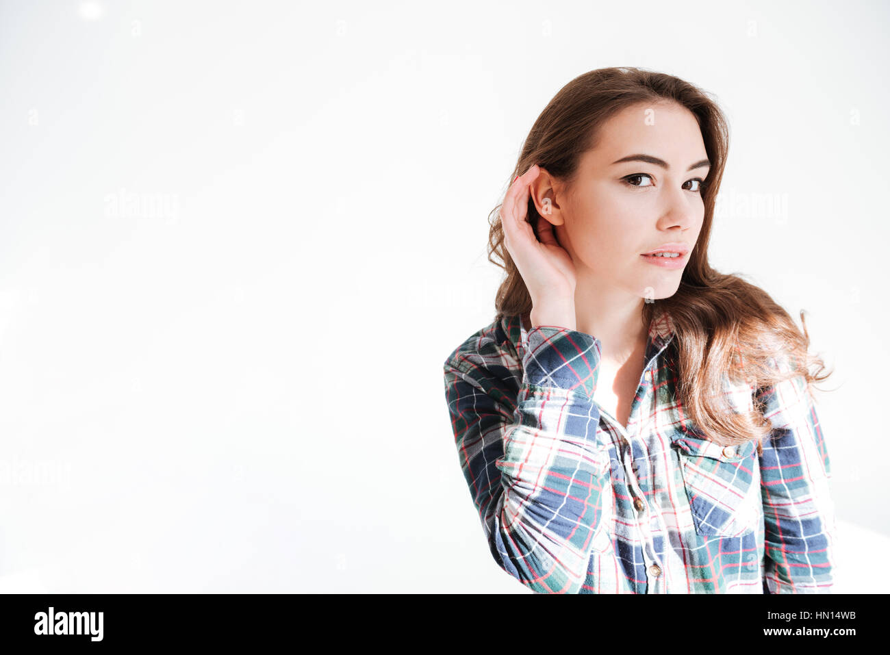 Pretty young woman standing with hand at ear to hear better isolated ...