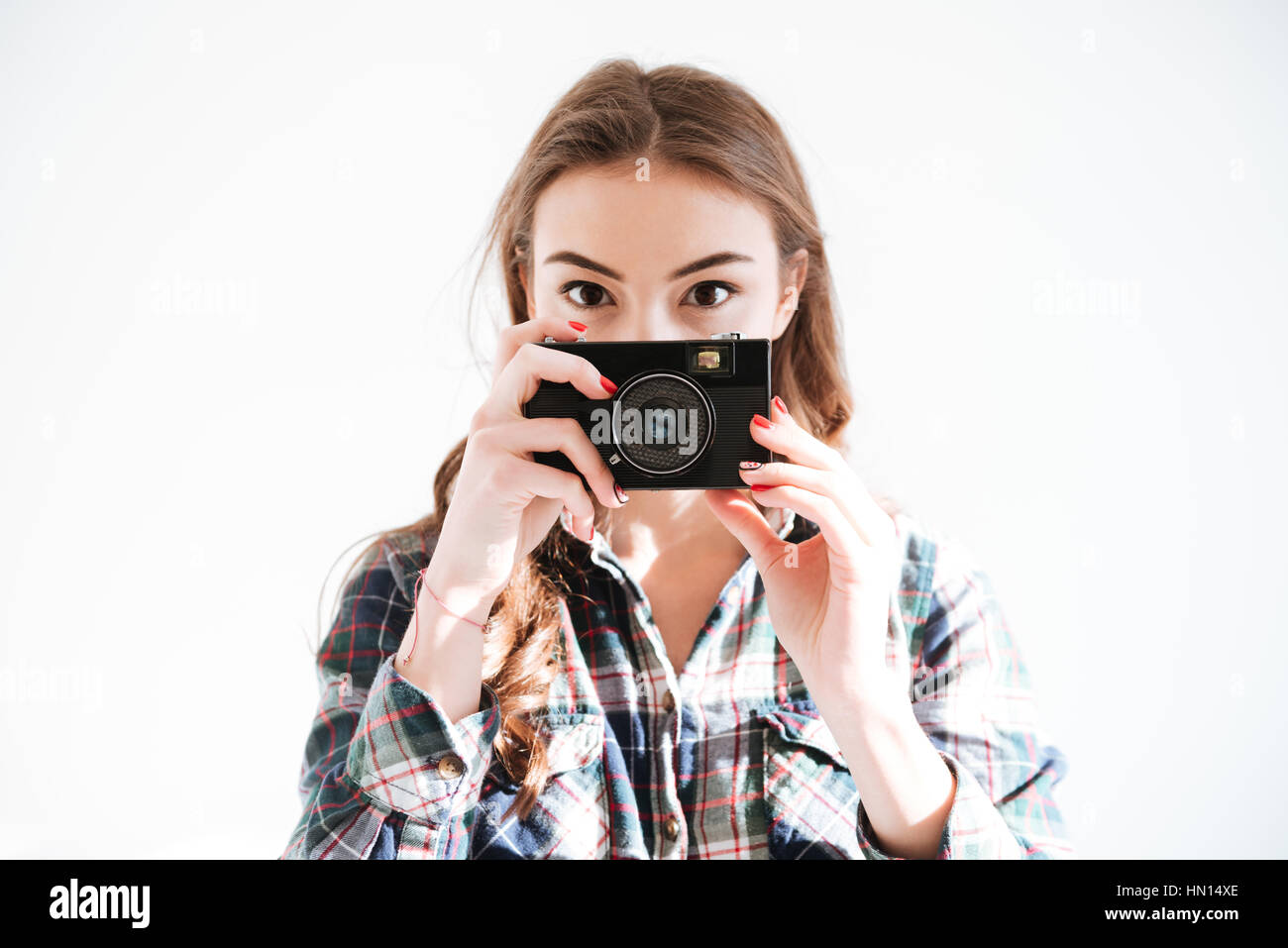 Picture of young woman holding camera while standing over white ...