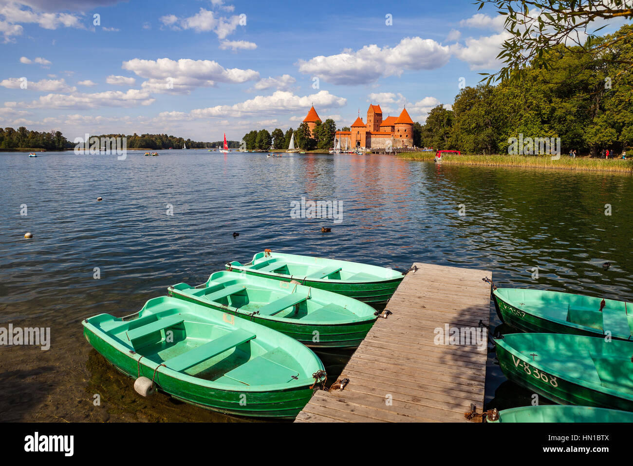 Green boats for tourists in water of Galve lake, Trakai castle on ...