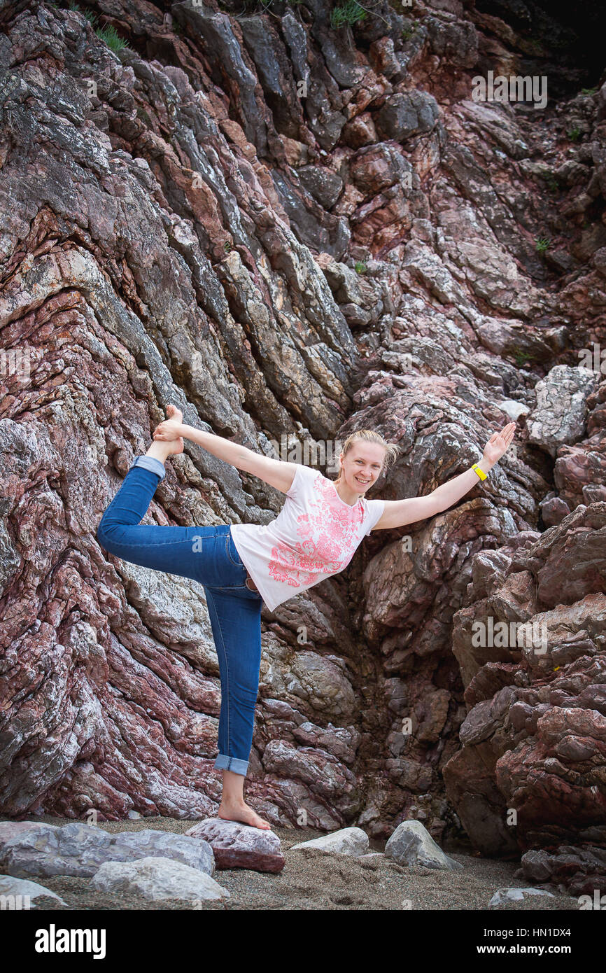 Young woman in a yoga pose on rock background Stock Photo - Alamy