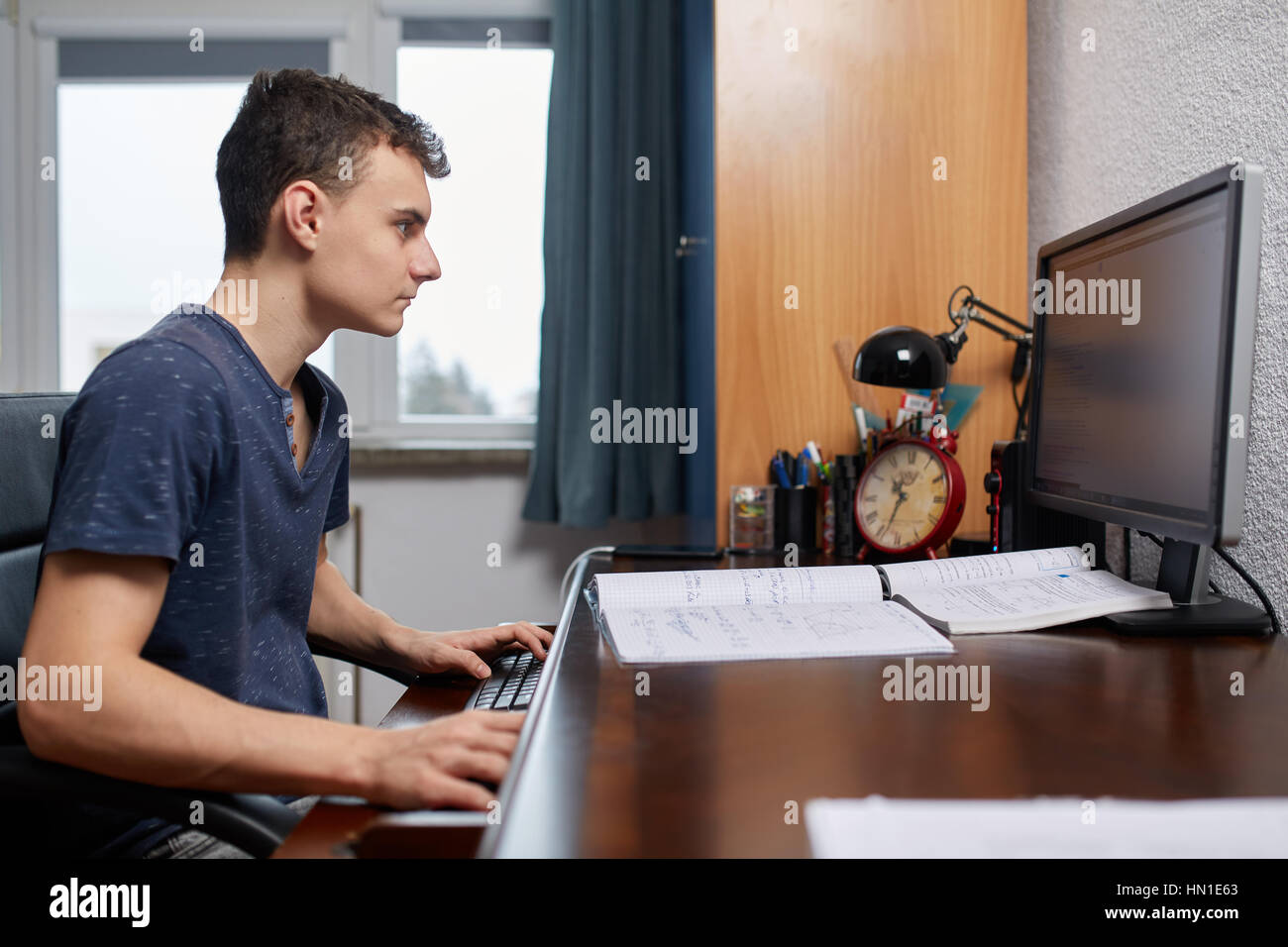 Teenage boy doing homework with the help of computer Stock Photo - Alamy
