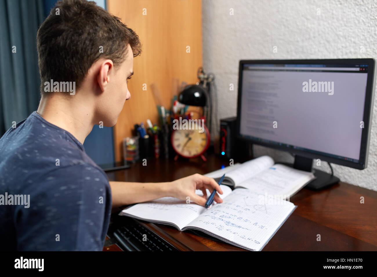 Teenage boy doing homework with the help of computer Stock Photo - Alamy