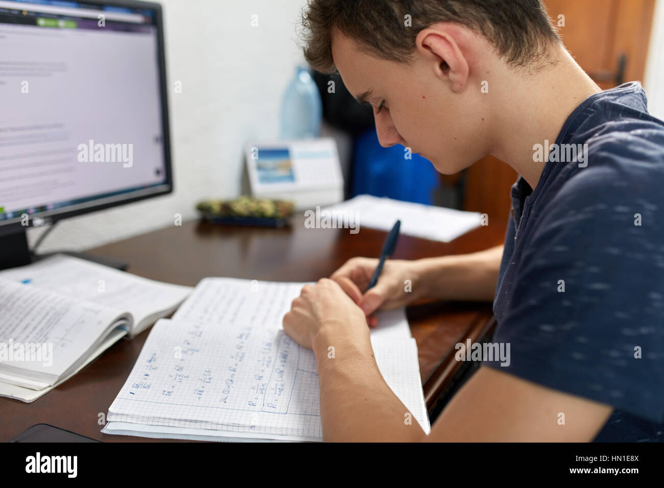 Teenage boy doing homework with the help of computer Stock Photo - Alamy