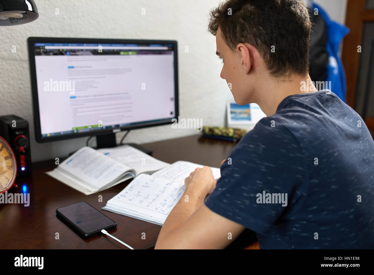 Teenage boy doing homework with the help of computer Stock Photo - Alamy