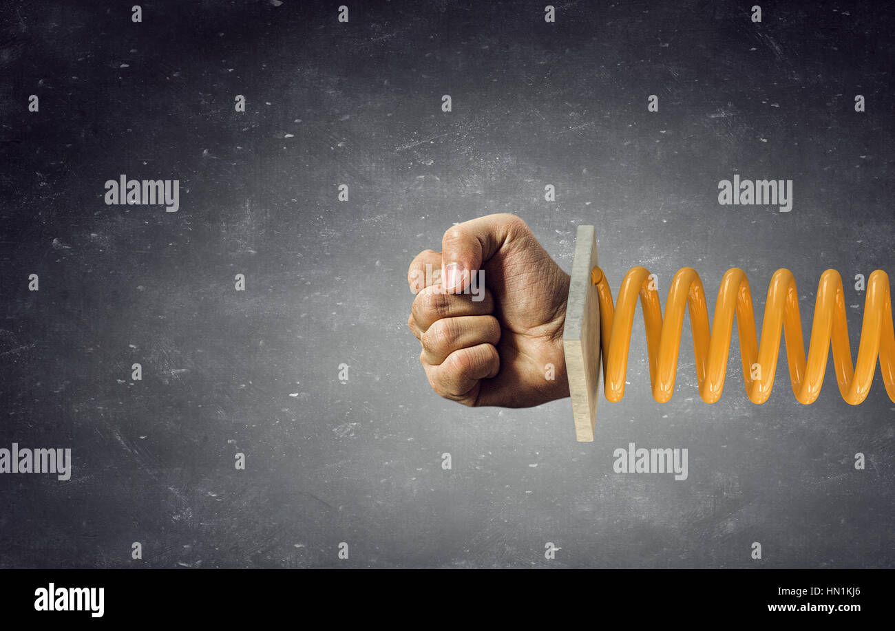 Human fist on spring against concrete background Stock Photo - Alamy