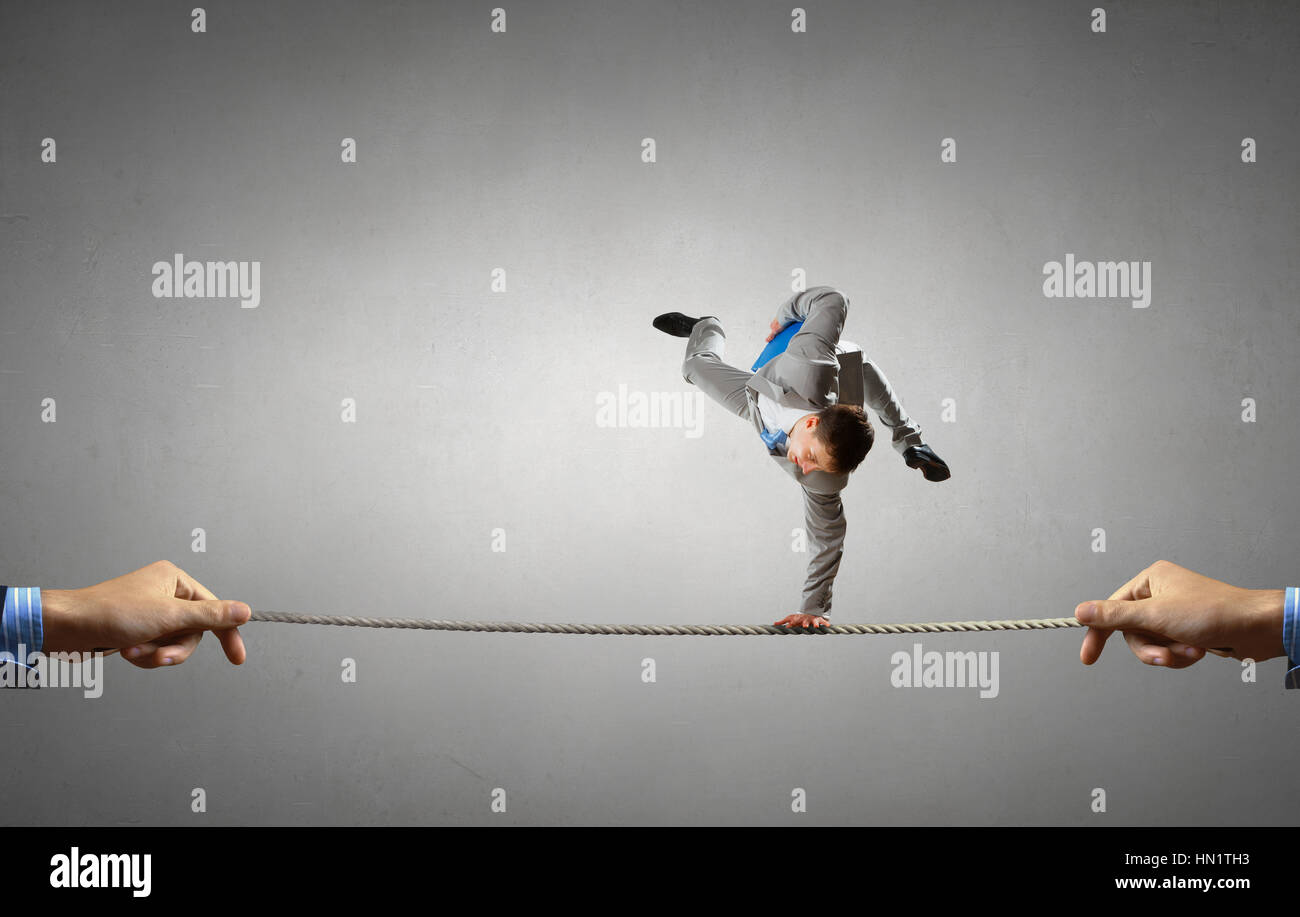 Young cheerful businessman doing handstand on strained rope Stock Photo ...