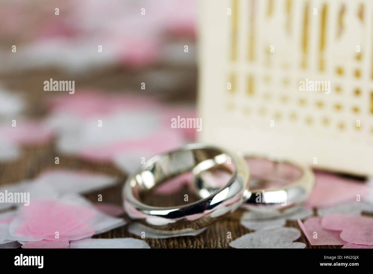 pair of white gold wedding rings on a wooden background with confetti ...