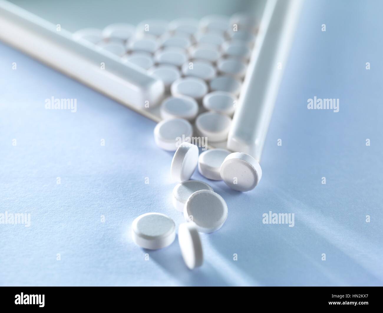Pills pouring out of measuring triangle Stock Photo - Alamy