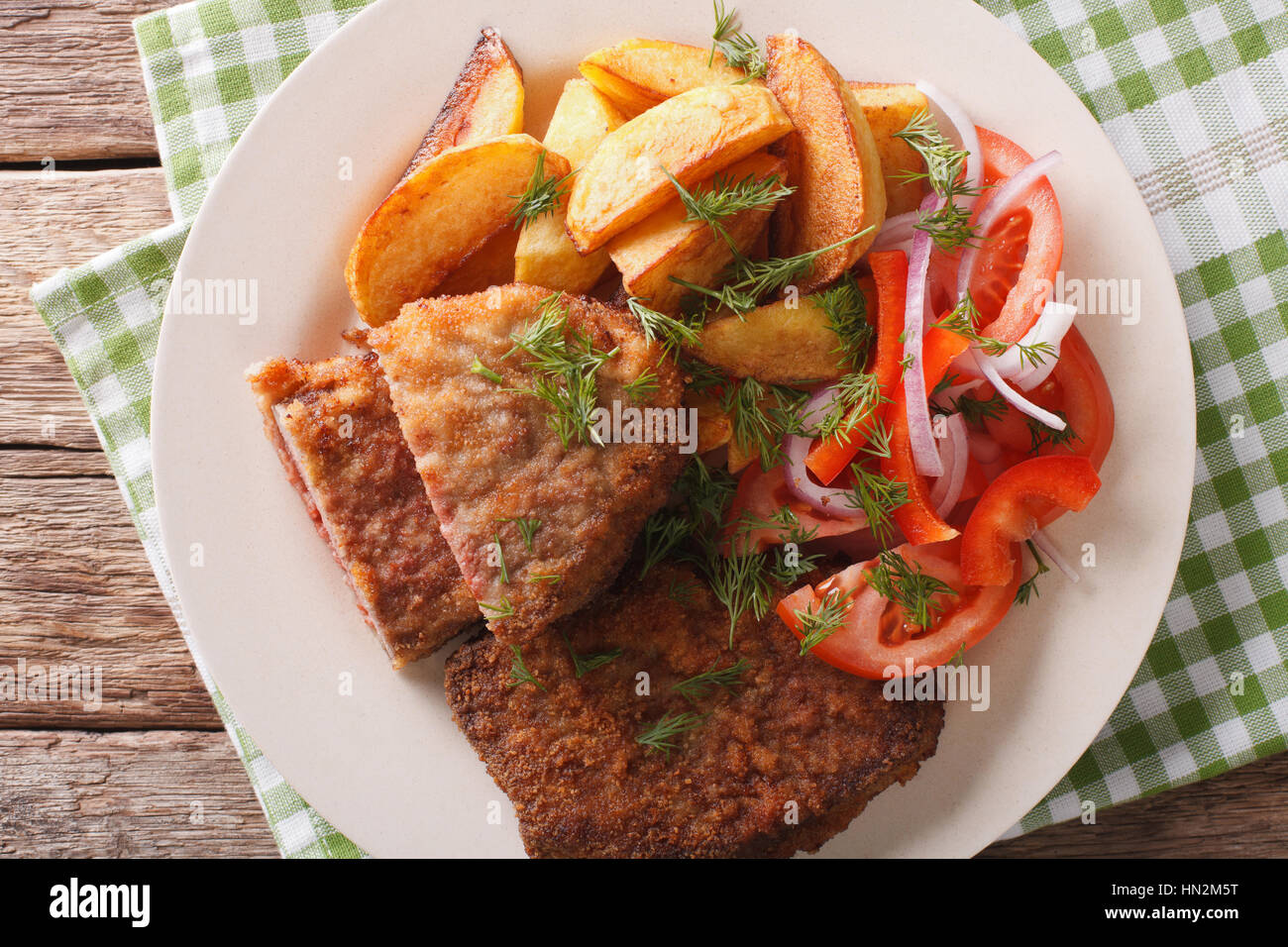Fried Breaded rump steak with potato and vegetables close-up on a plate ...