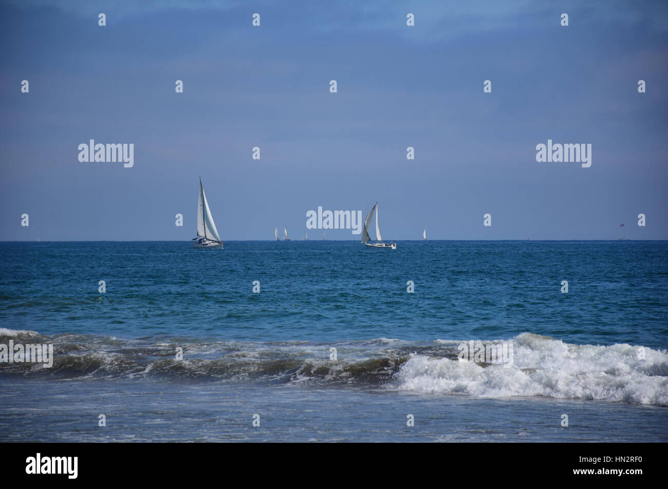 Peaceful sailing boat in open ocean at distance with blue sea and white ...
