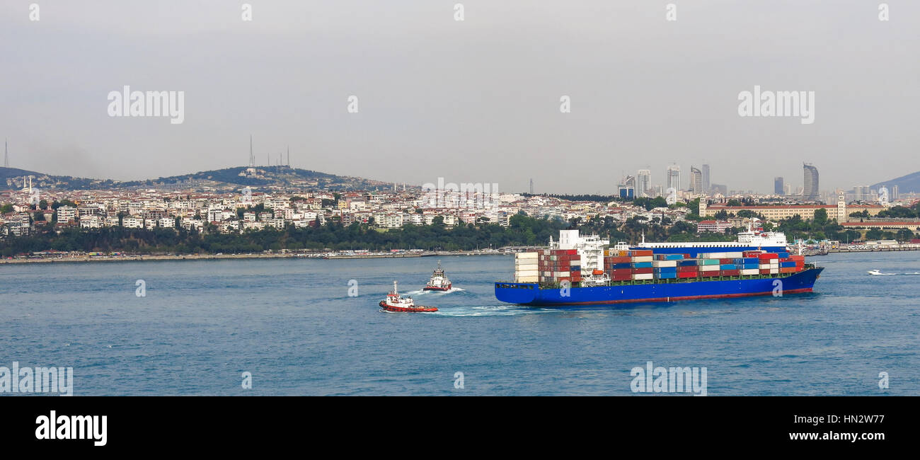 A cargo ship cruises in front of the skyscrapers and modern office ...