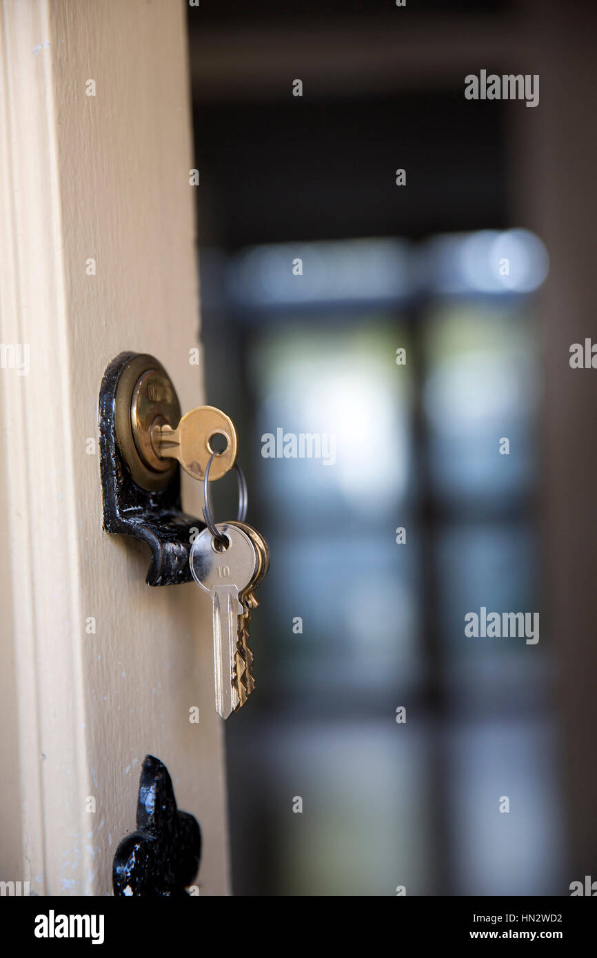A set of house keys are seen in a lock on the front door to a house in ...