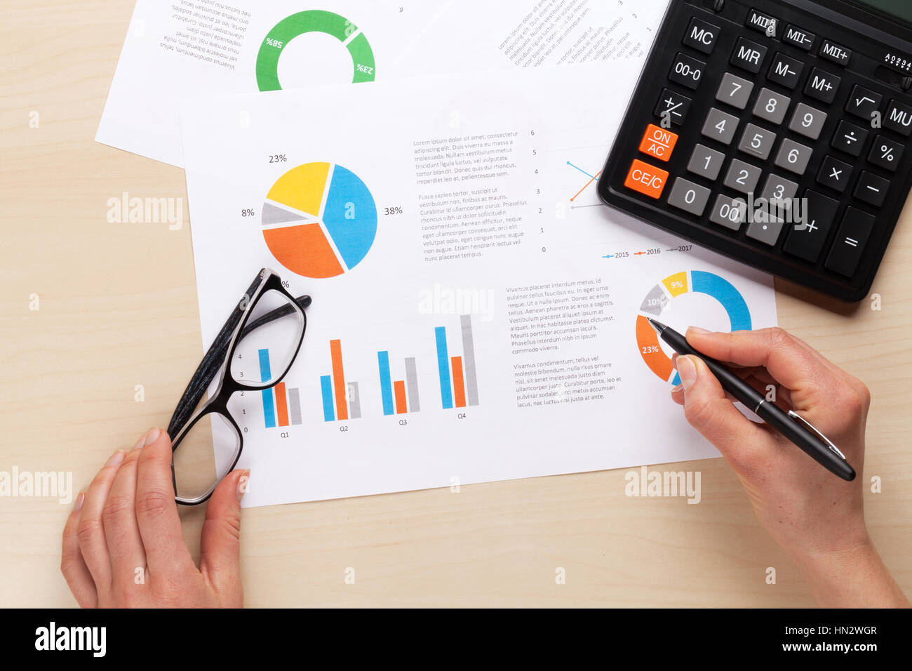Woman working with reports and charts over wooden office desk. Top view ...
