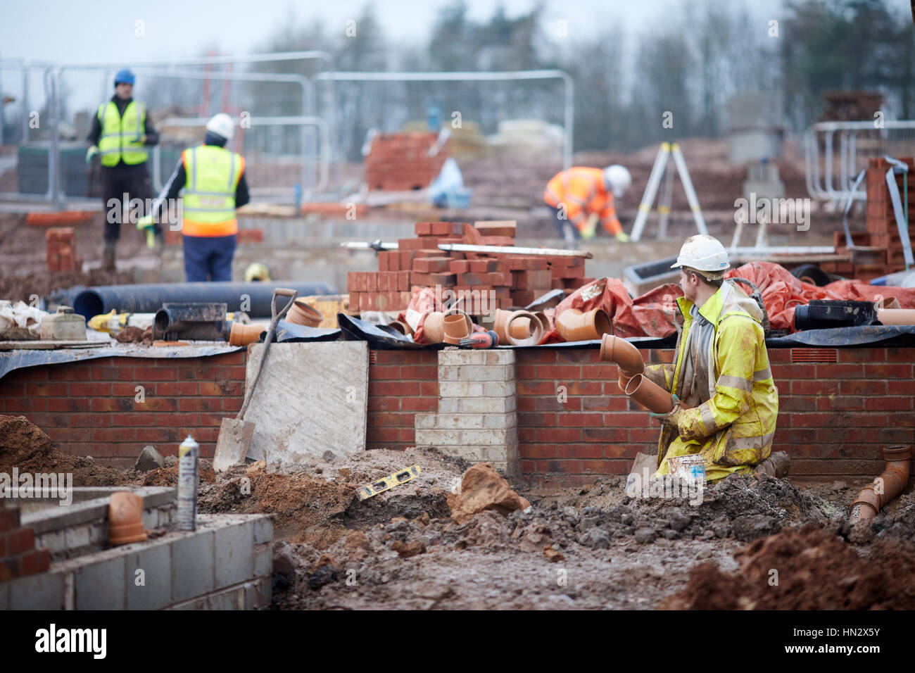 a young male builder working on a muddy new house building site ...
