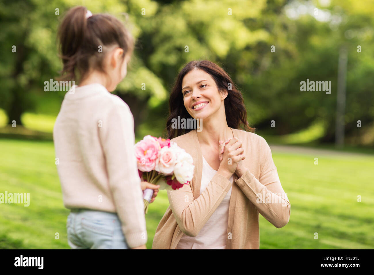 girl giving with flowers to mother in summer park Stock Photo - Alamy