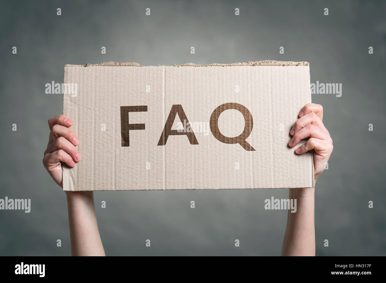 FAQ - Frequently Asked Questions text on cardboard held Stock Photo - Alamy