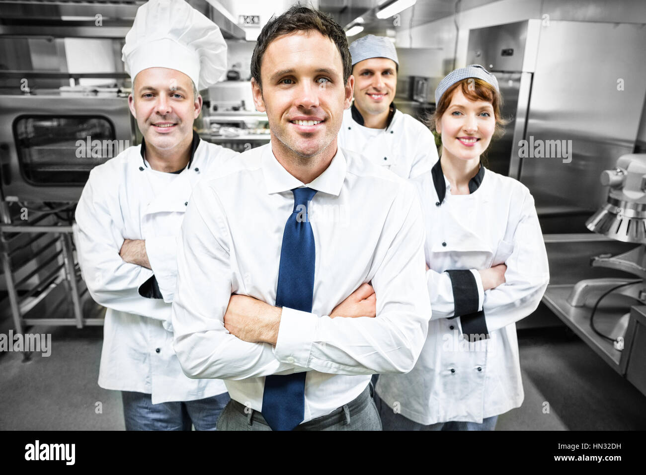 Restaurant manager posing in front of team of chefs smiling at camera ...