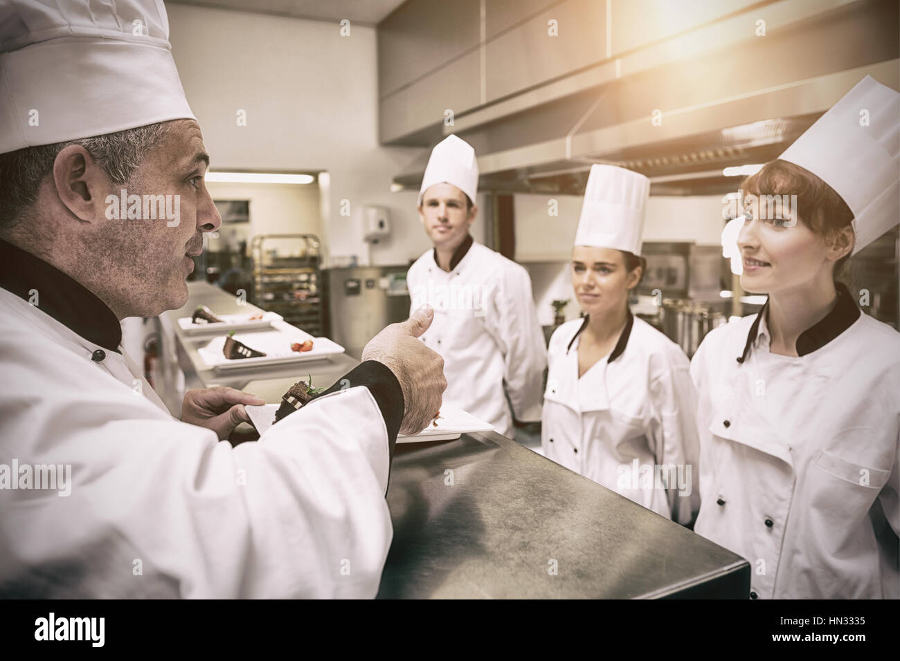 Head chef rating plate of one of his apprentices in kitchen Stock Photo ...