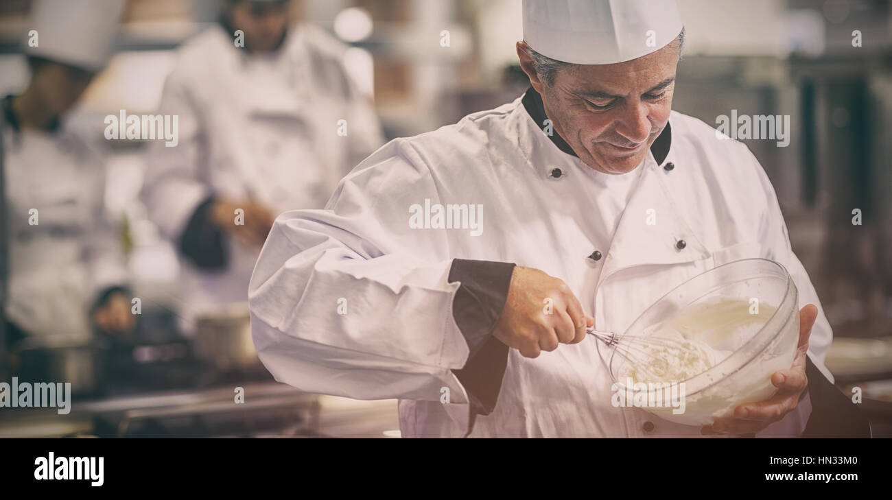 Happy chef whisking cream in kitchen Stock Photo - Alamy