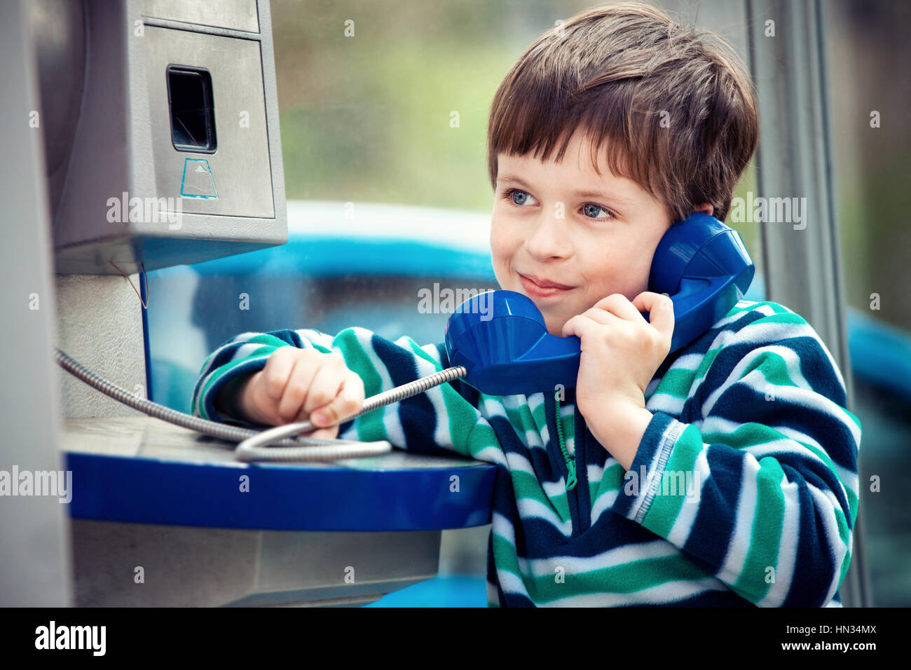 Cute little boy talking on the public phone Stock Photo - Alamy