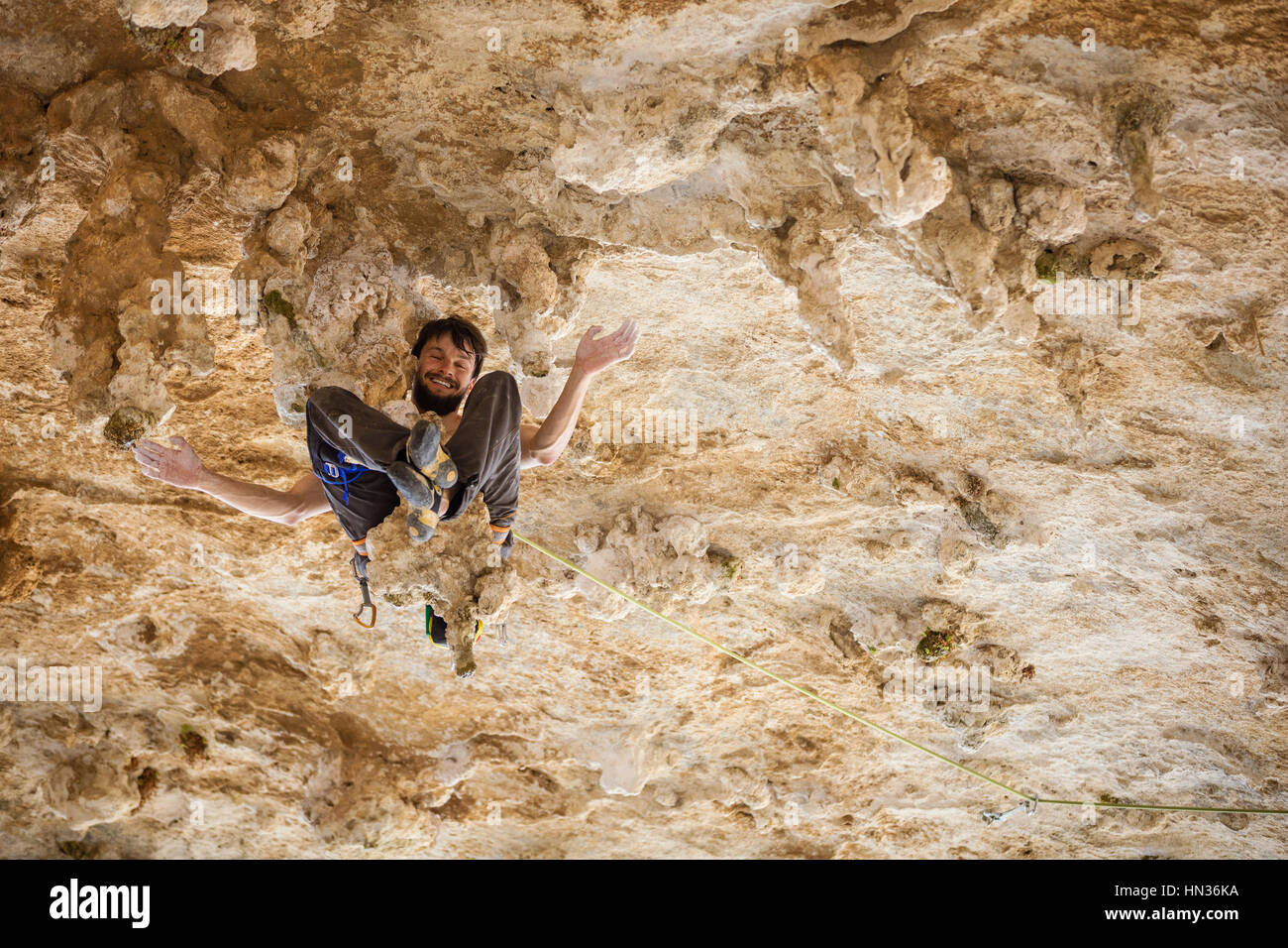 Cheerful rock climber resting while sitting on calanet before next ...