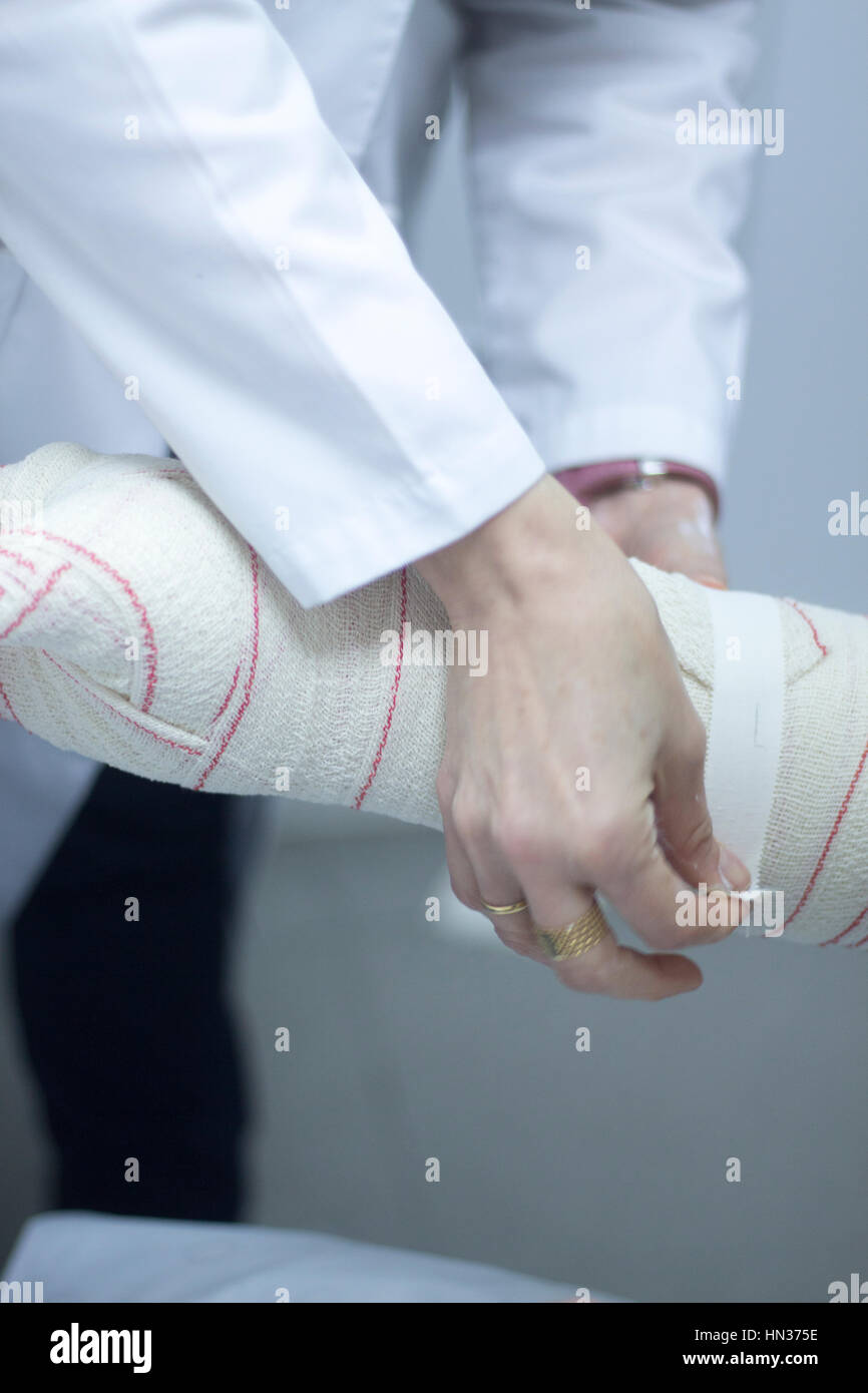 Doctor applying a plaster cast and bandages to patient forearm and ...