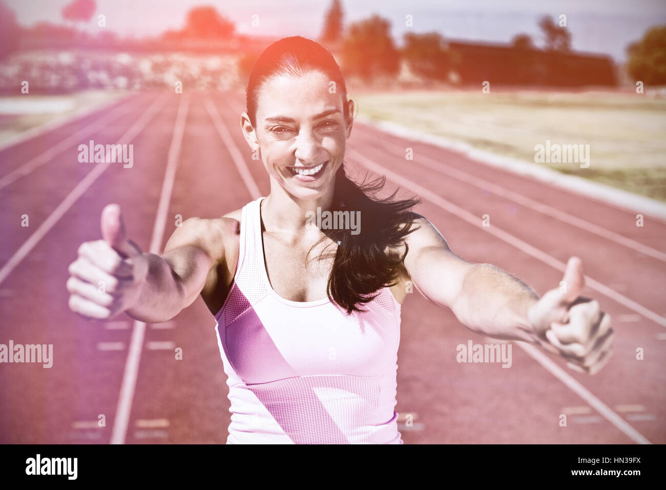 Portrait of female athlete showing thumbs up on running track Stock ...