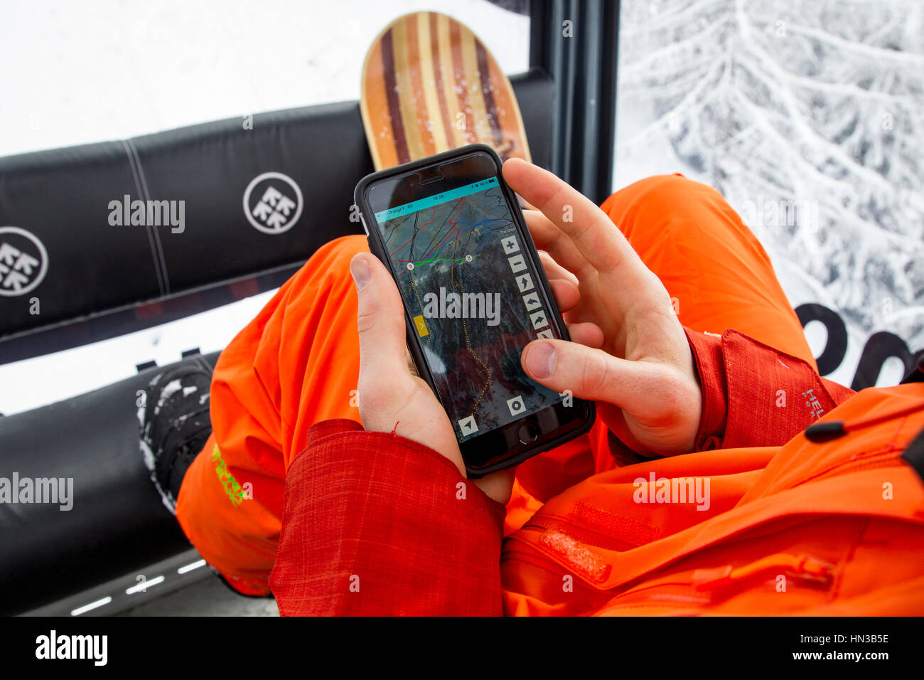Snowboarder using a phone to check the free ride lines in the lift ...