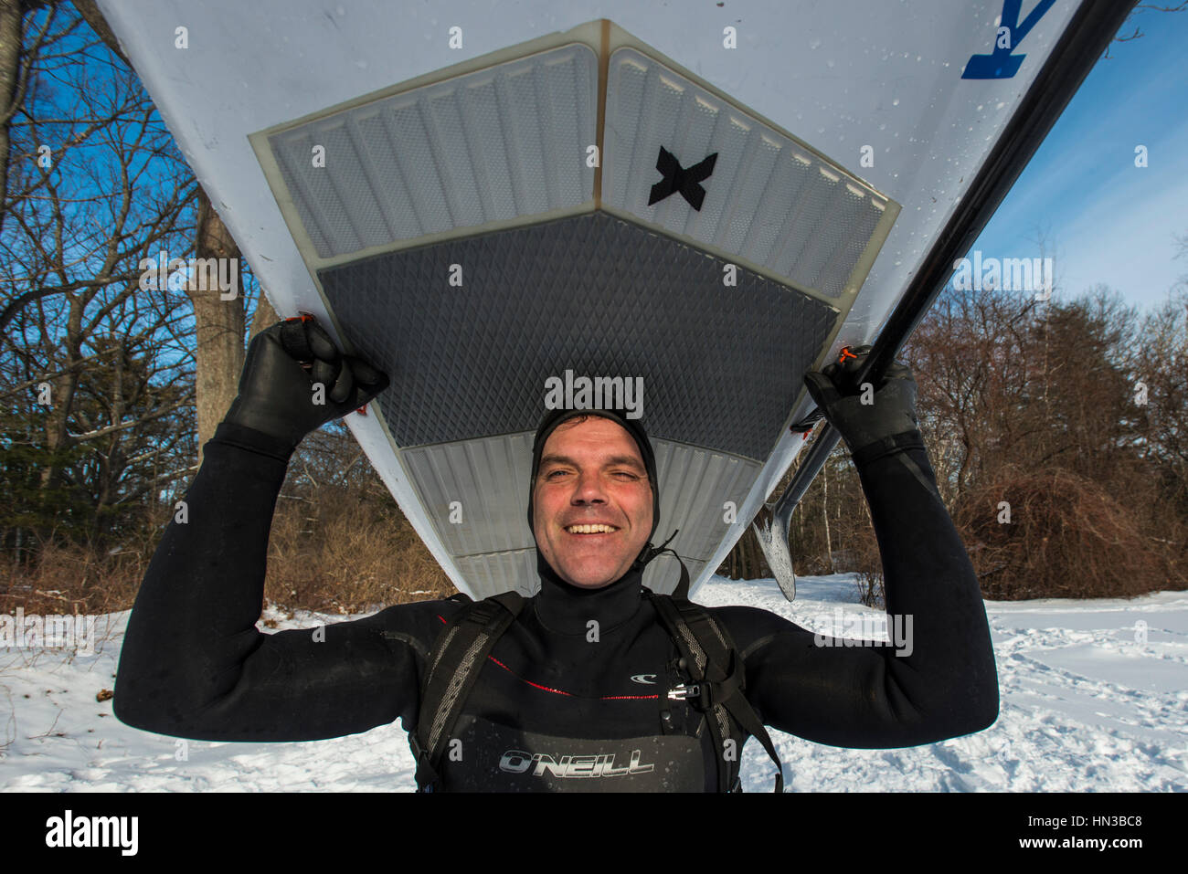 Portrait Of Smiling Paddleboarder Carrying Paddleboard Off The Coast Of ...