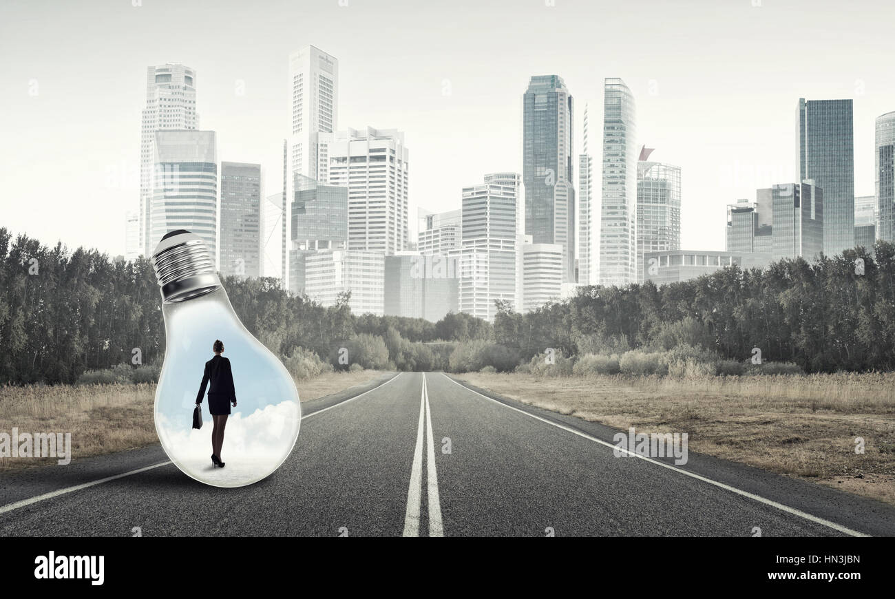 Young businesswoman trapped inside of light bulb on asphalt road Stock ...
